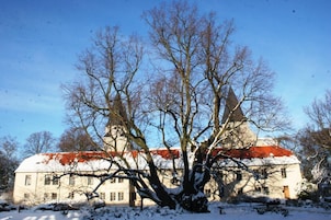 Um edifício com telhado vermelho, rodeado por árvores cobertas de neve e um céu azul límpido.
