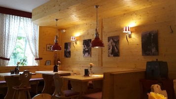 Interior de madeira com área de jantar, paredes de madeira e luminárias vermelhas pendentes.
