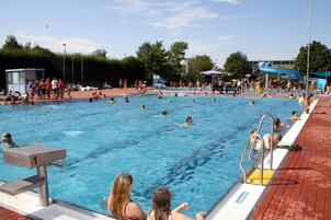 Piscina pública com várias pistas de natação, cadeiras de salva-vidas e uma torre de salva-vidas.