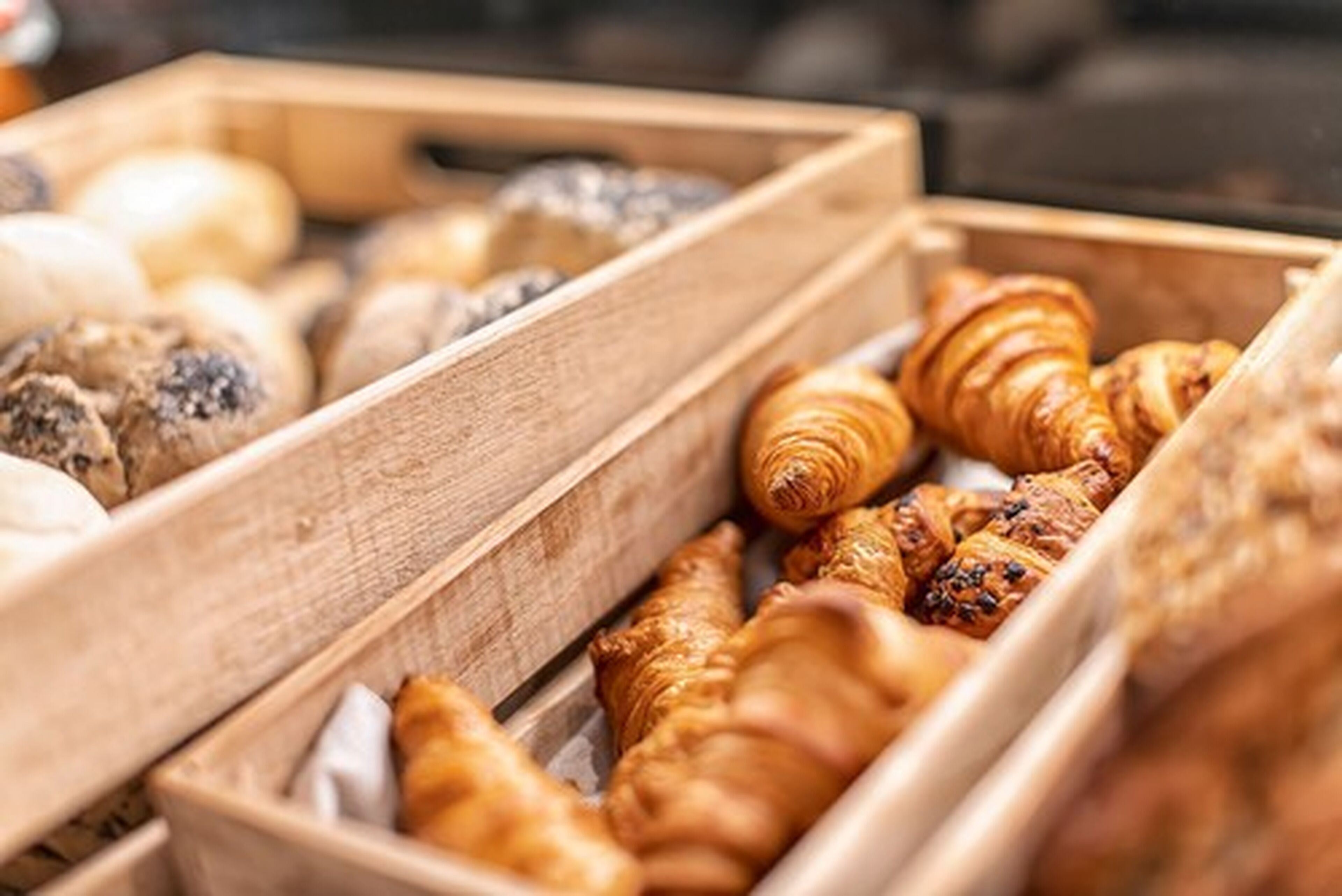 Uma vitrine de madeira com diversos produtos de panificação, incluindo pão e pastelaria.