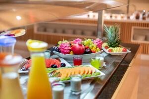 Um buffet com diversas frutas, legumes e bebidas.