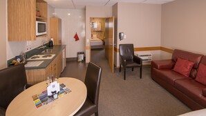 Quarto de hotel compacto com cozinha compacta, área de refeições, sofá e uma cama de solteiro.