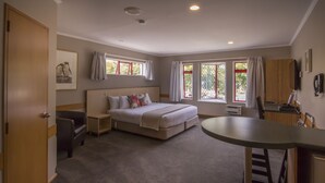 Quarto com cama, mesas de cabeceira, escrivaninha e cadeira.