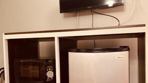 Cozinha compacta equipada com micro-ondas, frigorífico e televisão montada acima.