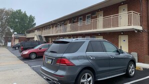 Um motel de vários andares com fachada de tijolos e varanda no segundo pavimento.