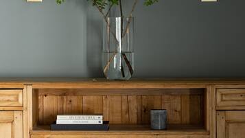 Um console de madeira com um vaso de flores e duas arandelas fixadas na parede.