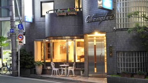 Um edifício moderno com uma grande entrada de vidro, uma placa com a inscrição "Changlee" e área externa com cadeiras e uma mesa.