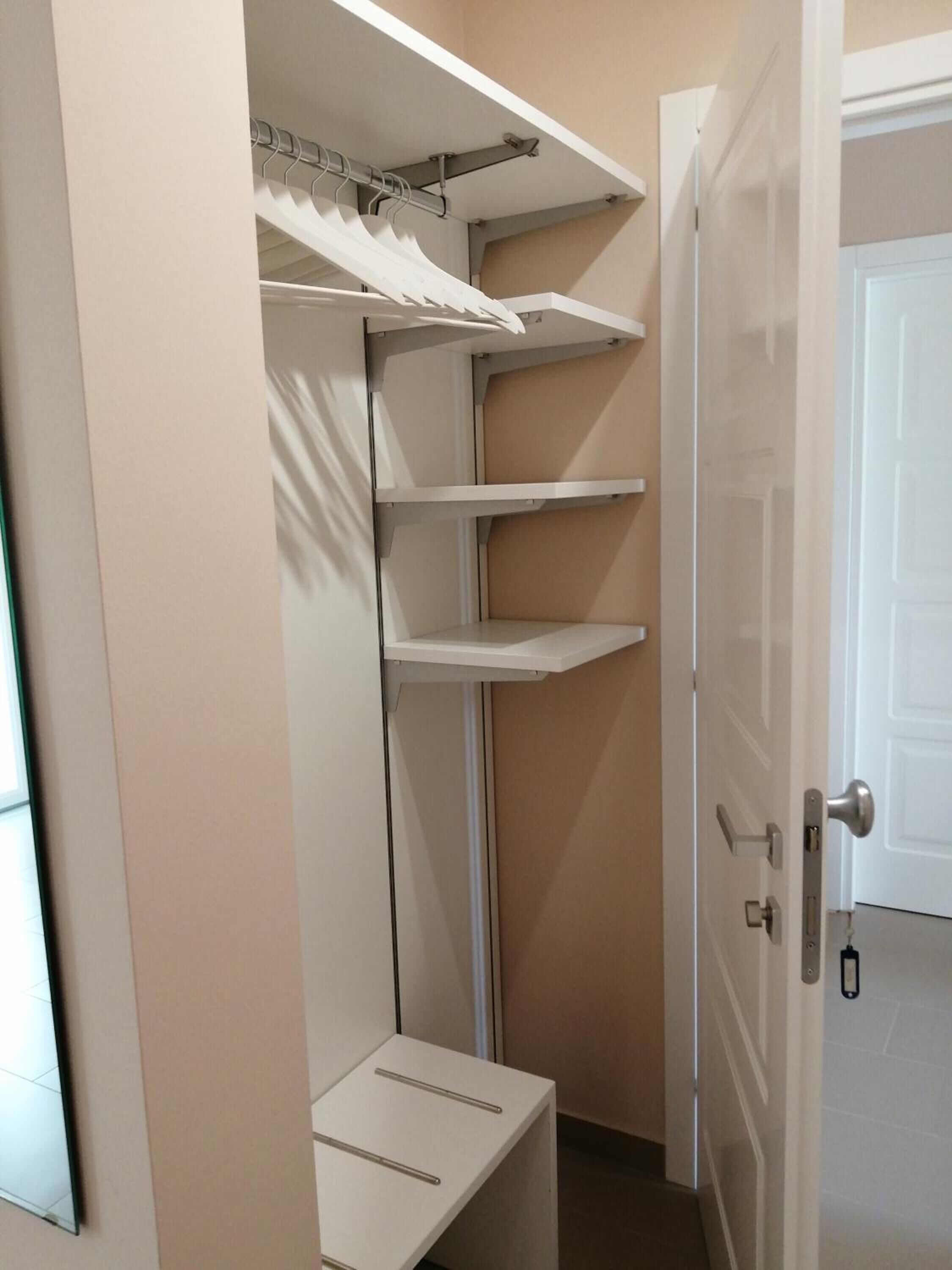 Um armário com prateleiras abertas e uma porta.