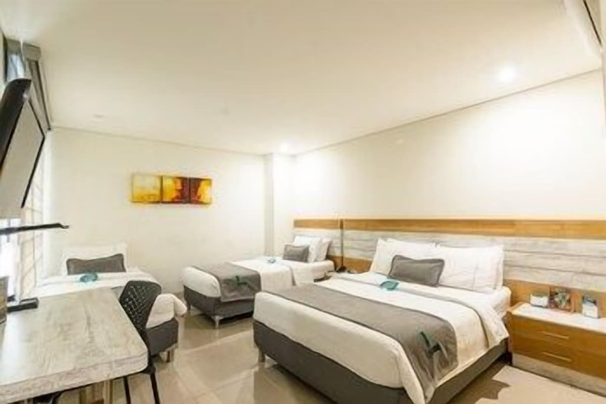 Quarto de hotel com duas camas, uma mesinha e um criado-mudo.