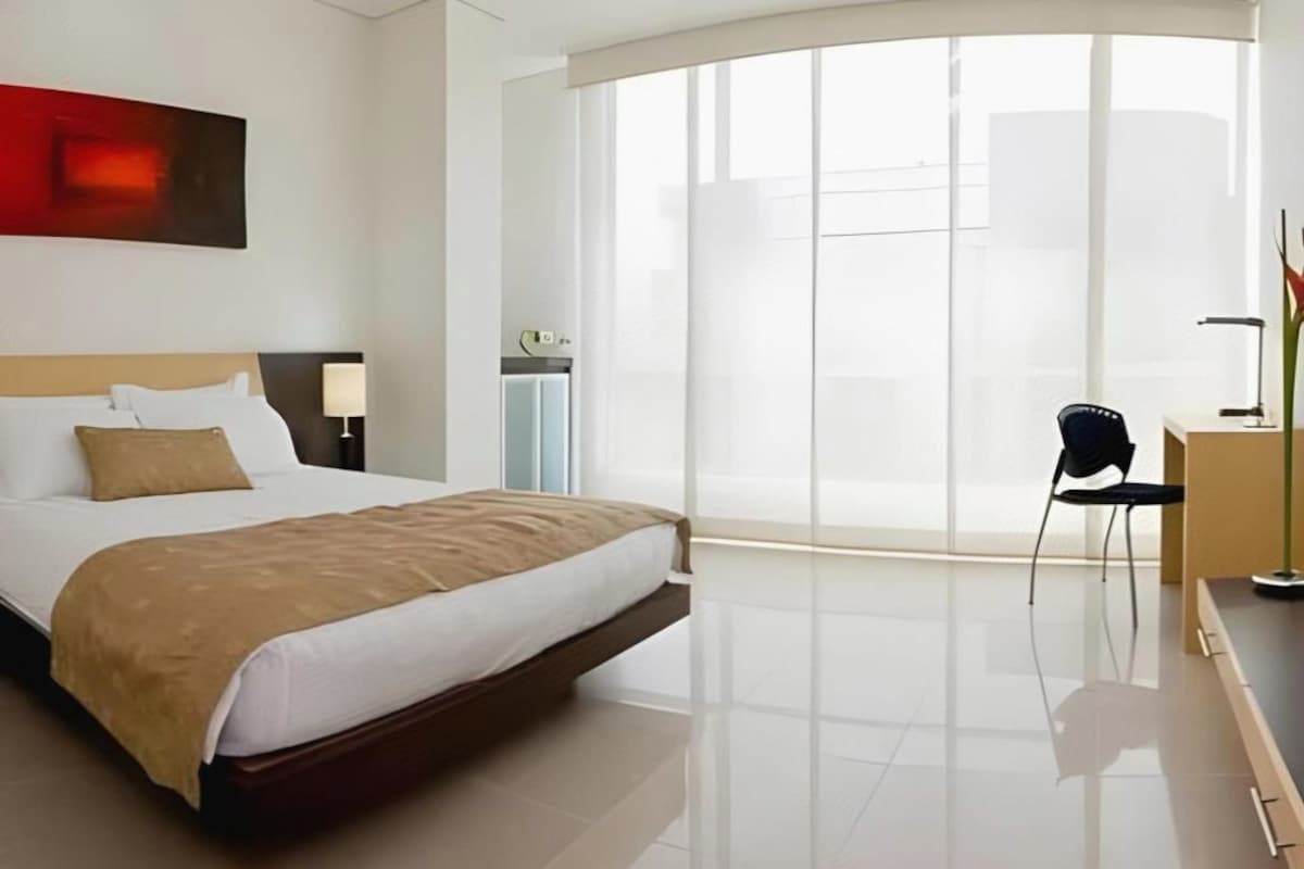 Quarto de hotel moderno com uma cama grande, uma mesa e uma cadeira.