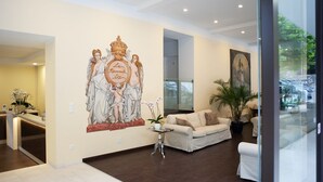 Uma área de recepção com um letreiro 'WELCOME', um mural grande, um sofá e um painel de vidro.