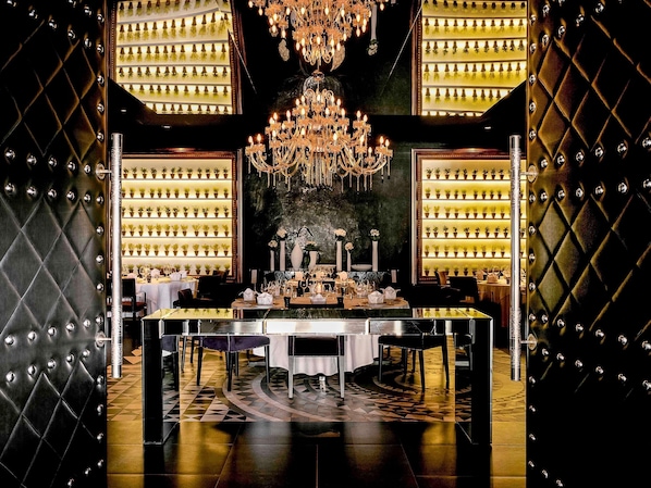 Uma sala de jantar luxuosa com um candelabro, plantas em vasos e um piso estampado.