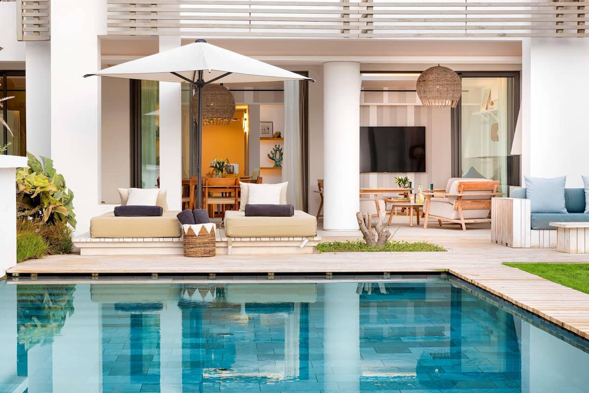 Uma área de estar externa moderna com piscina, assentos e espaço para refeições.
