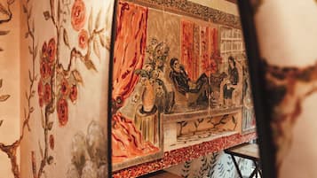 Quarto com um mural retratando uma cena histórica, uma mesa de madeira e uma cadeira.