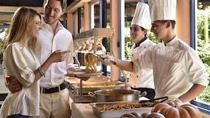 Buffet montado com várias estações de comida e um chef a servir refeições.