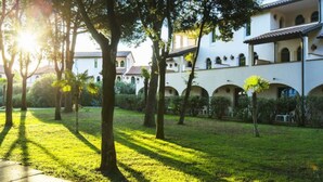 Um pátio com um edifício com arcadas e um gramado.