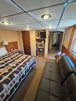 Quarto de hotel com cama, sofá, televisão e micro-ondas.