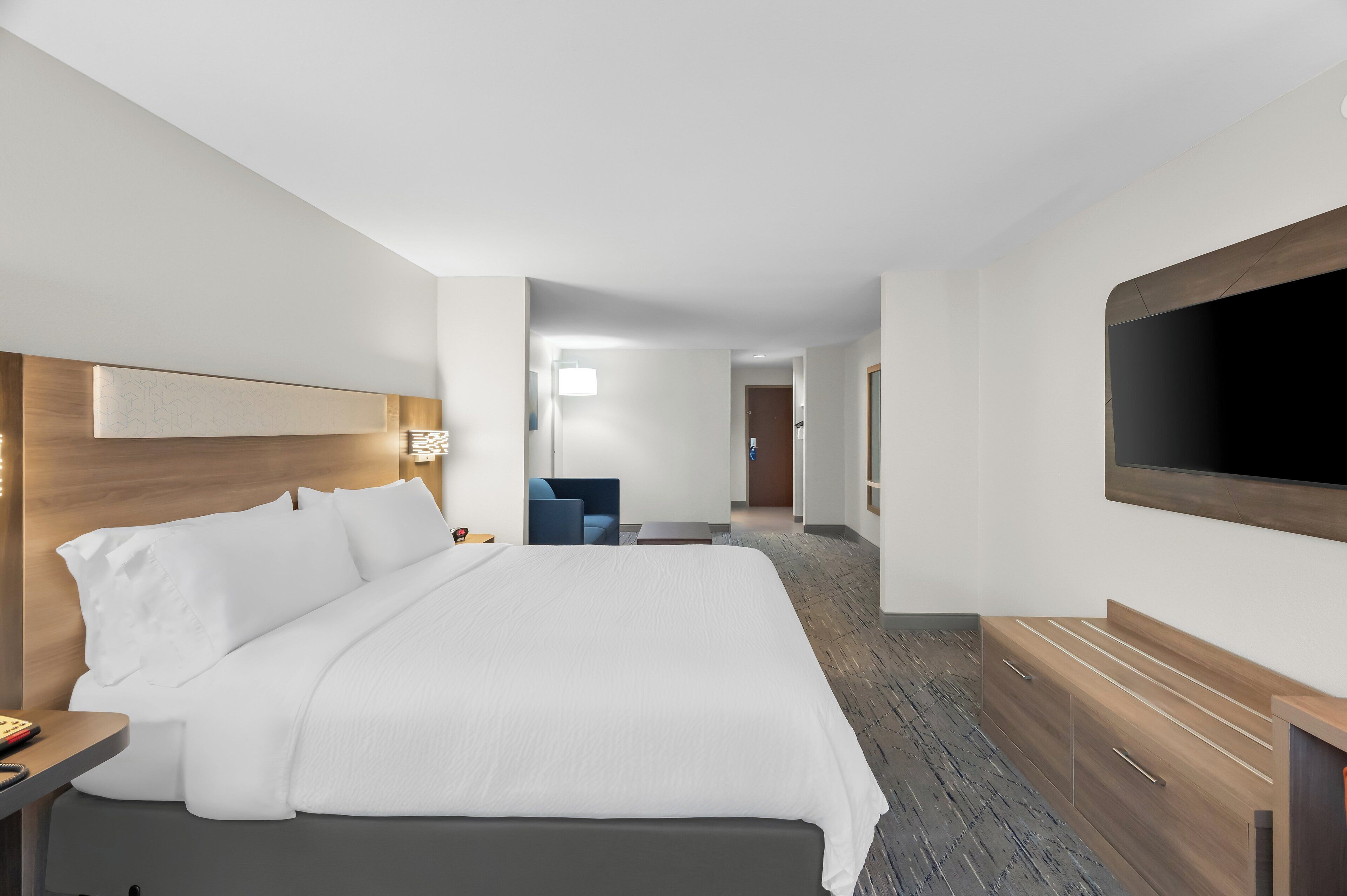 Quarto de hotel moderno com uma cama grande, mesas de cabeceira, uma TV de tela plana e cabeceira de madeira.