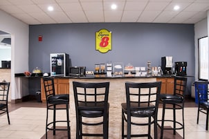 Um café Super 8 com área de bar, mesas e uma máquina de café.