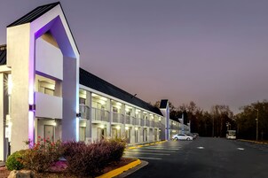 Um hotel de vários andares com design moderno, com uma série de varandas e estacionamento.
