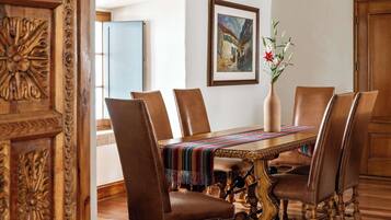 Uma sala de jantar com uma mesa de madeira, cadeiras de couro, um candelabro e um quadro na parede.