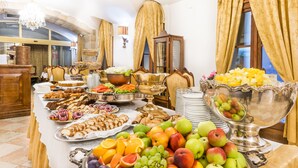 Uma mesa de buffet com diversos alimentos e uma grande tigela de frutas.