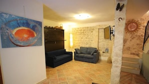 Uma sala de estar com dois sofás, uma mesa de jantar e uma parede de pedra.