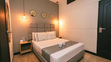 Quarto de hotel com cama, mesas de cabeceira, porta e decoração na parede.