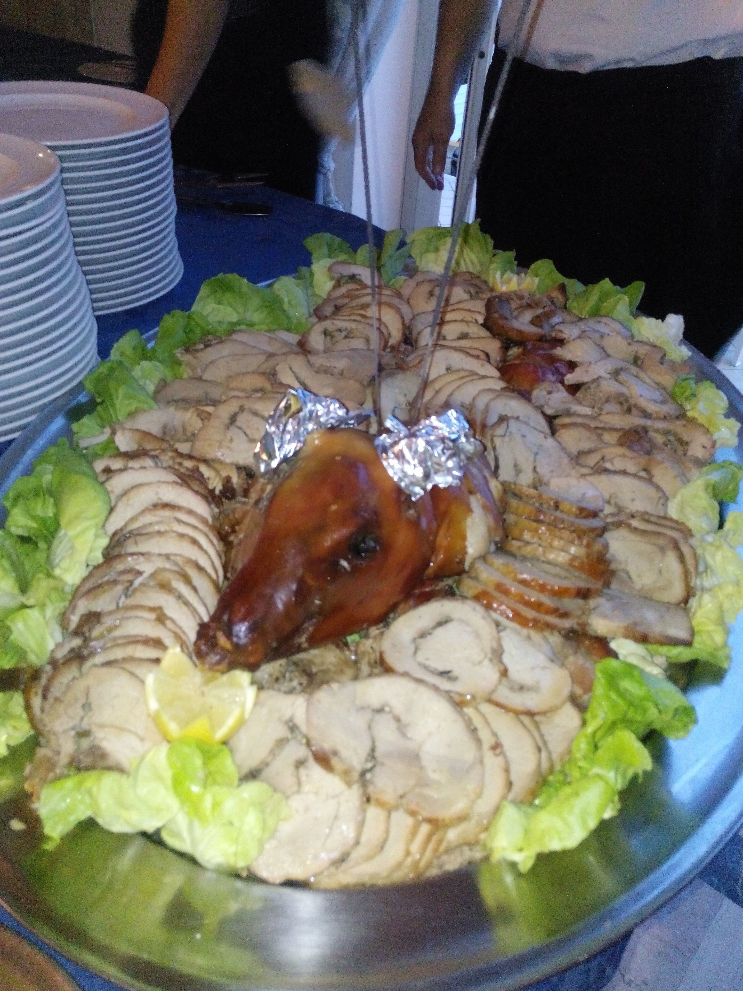 Uma grande travessa com fatias de carnes e vegetais, possivelmente para um buffet.