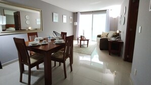 Uma sala de jantar com uma mesa posta para quatro pessoas, um sofá e uma mesa de centro.