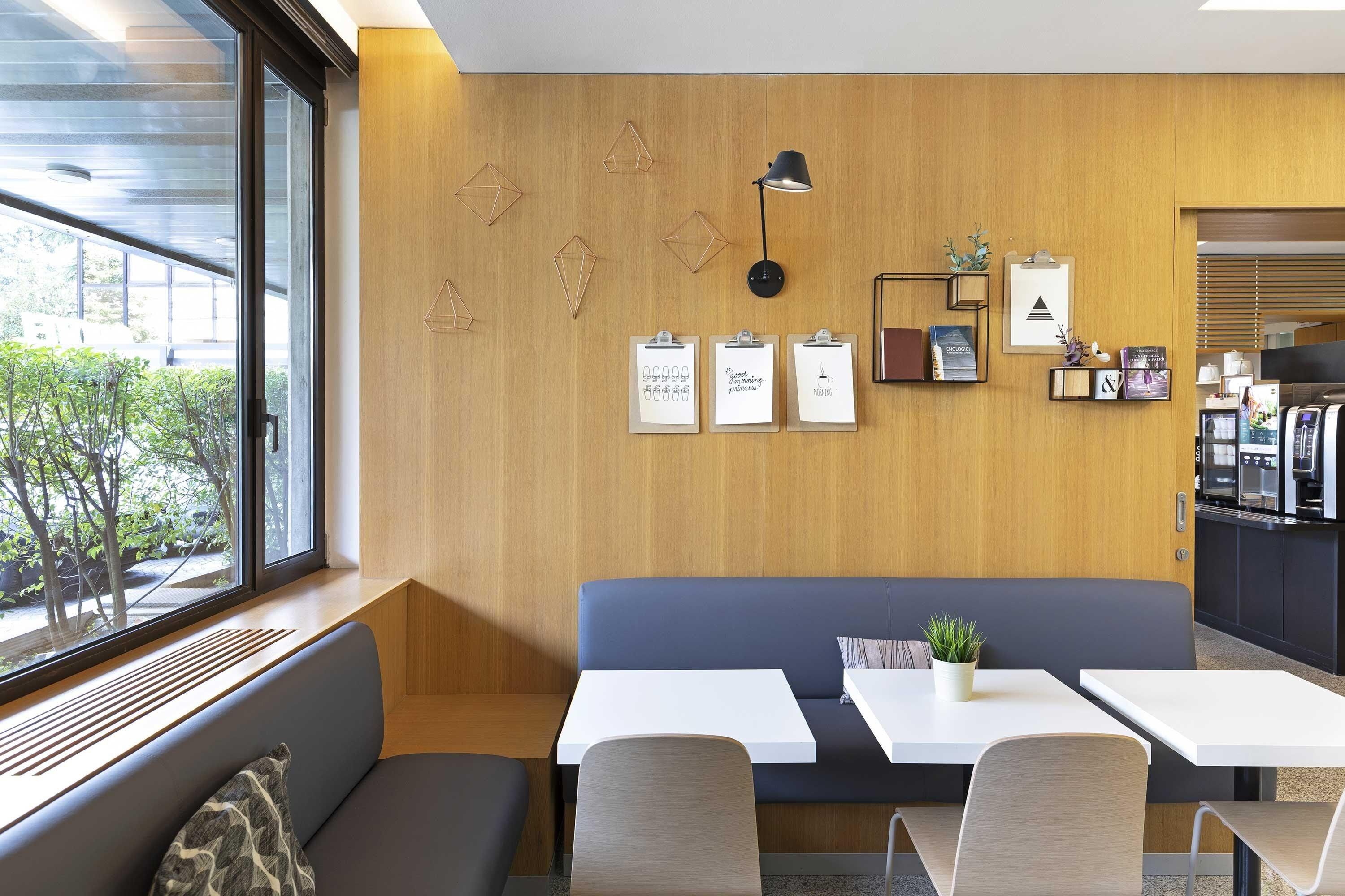 Interior moderno com parede de madeira, sofá azul e pequena mesa com cadeiras.
