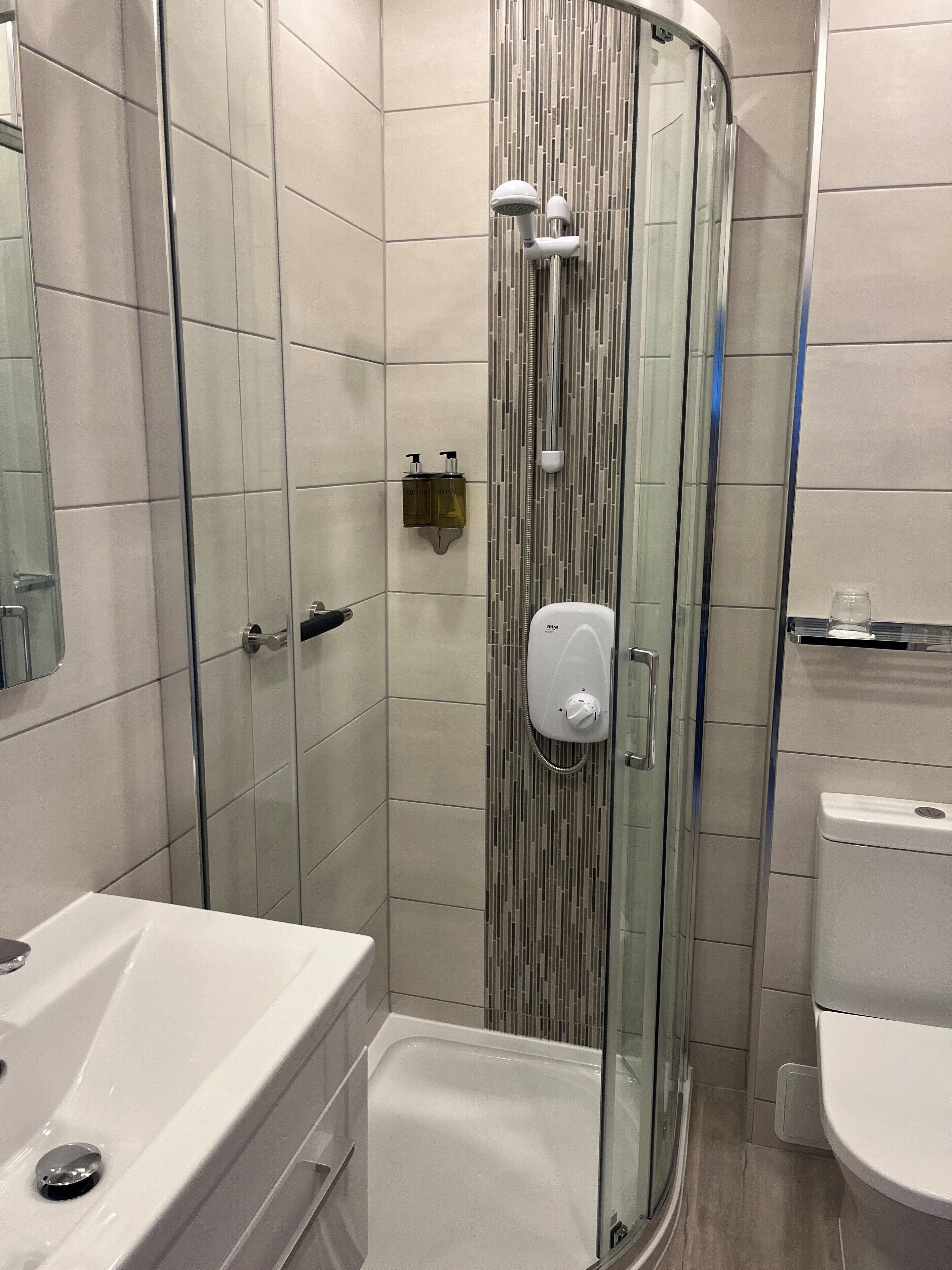 Um banheiro moderno com box de vidro, pia branca e vaso sanitário.