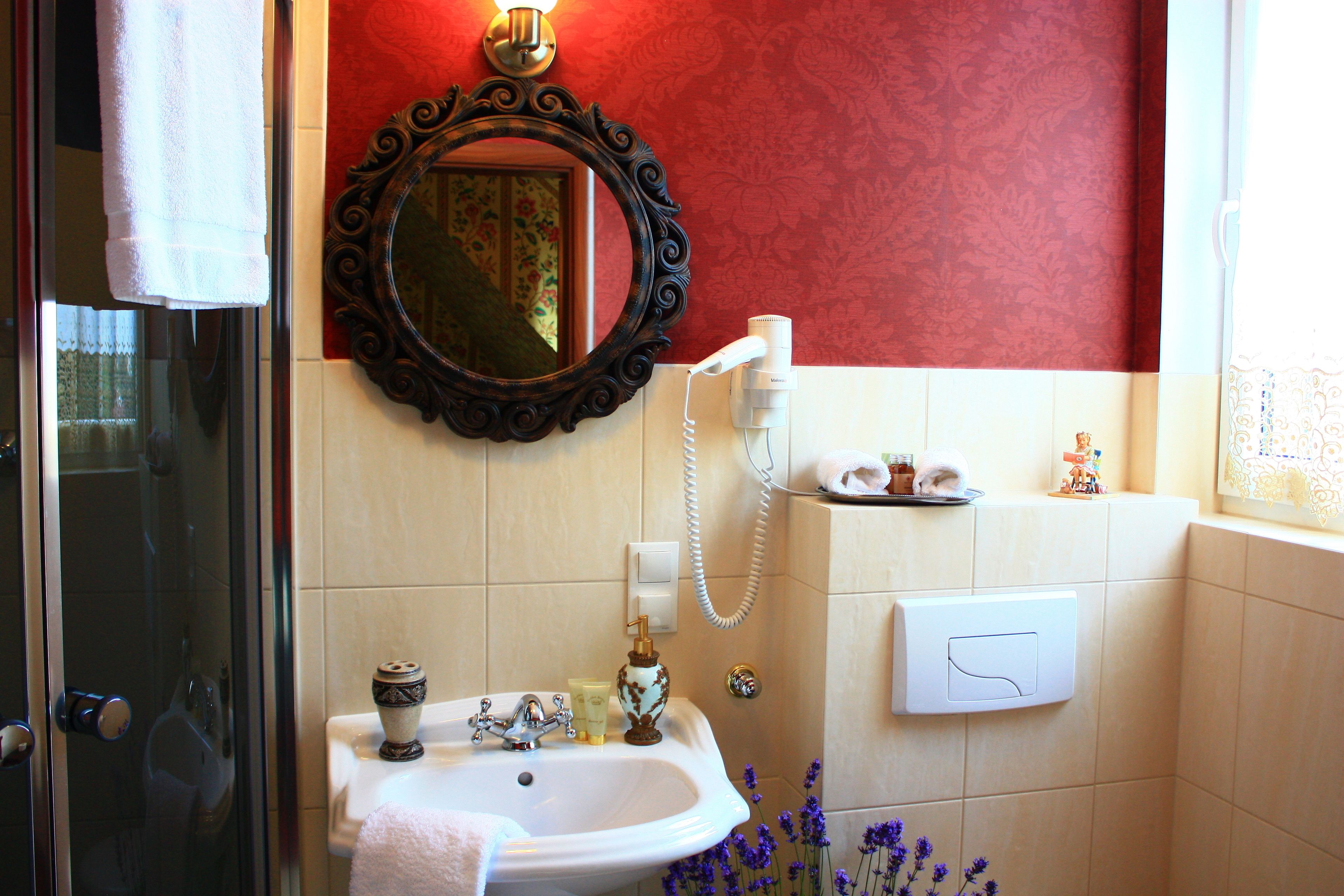 Uma casa de banho com lavatório, espelho e secador de cabelo na parede.