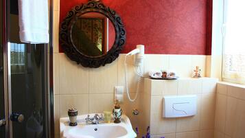 Uma casa de banho com lavatório, espelho e secador de cabelo na parede.