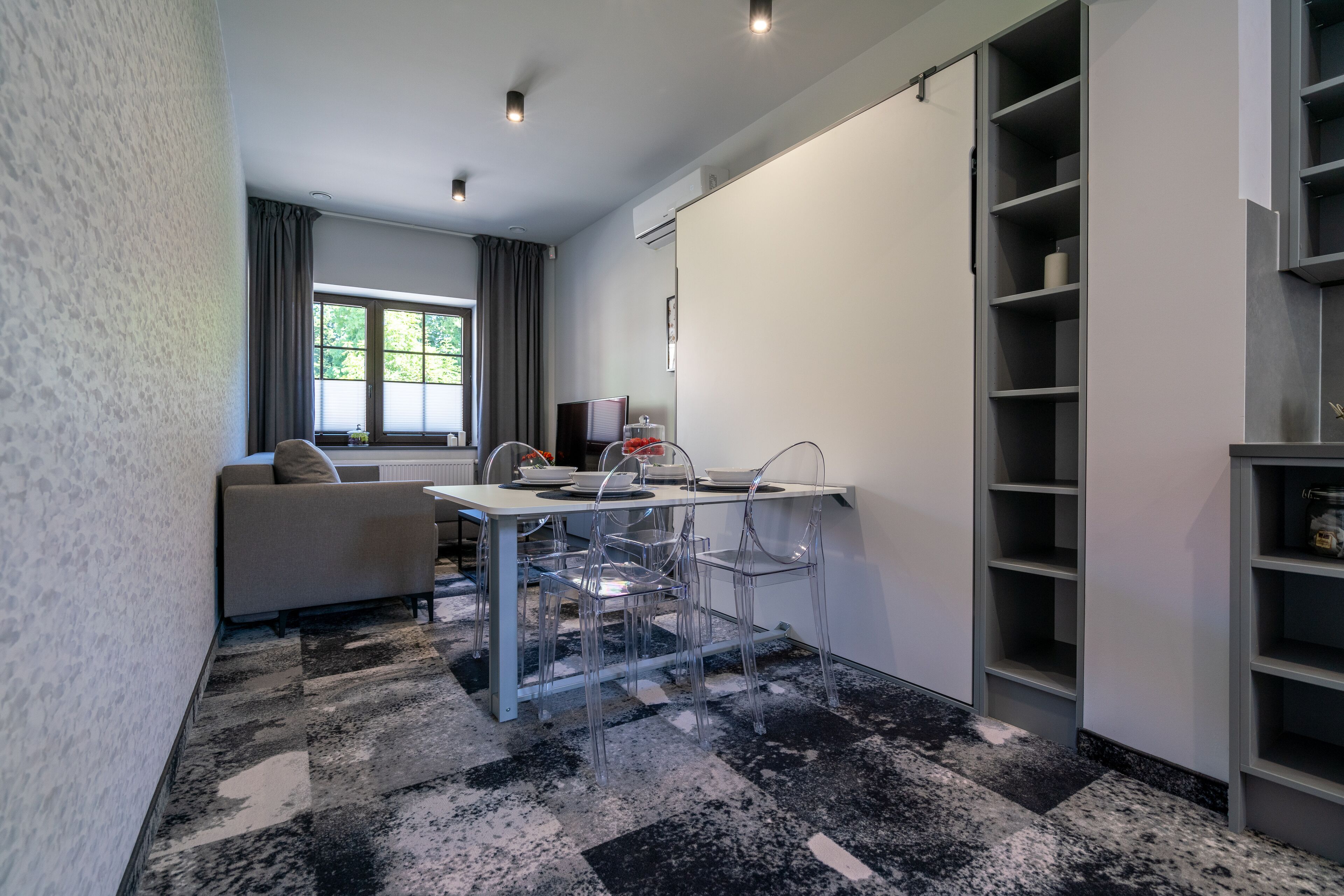 Quarto moderno com mesa de jantar, cadeiras, sofá e estante embutida.