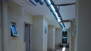 Um corredor com piso de azulejos, várias portas e uma escadaria que dá acesso a um andar superior.