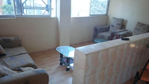 Uma sala de estar com um conjunto de sofás, uma mesa de centro de vidro e um separador revestido de azulejos.
