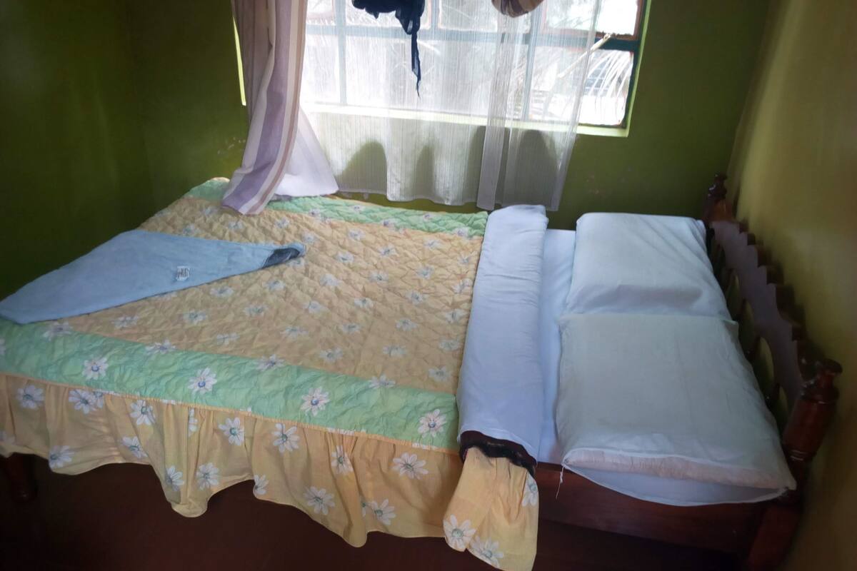 Uma cama com colcha florida, almofadas brancas e manta azul.