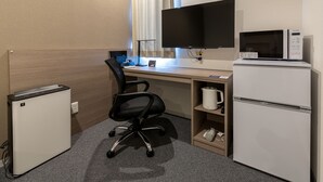 Quarto de hotel com escrivaninha, cadeira de escritório preta, TV de tela plana, micro-ondas, mini-geladeira e cafeteira.