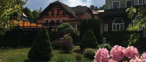 Um edifício tradicional em estilo europeu com um jardim na frente.
