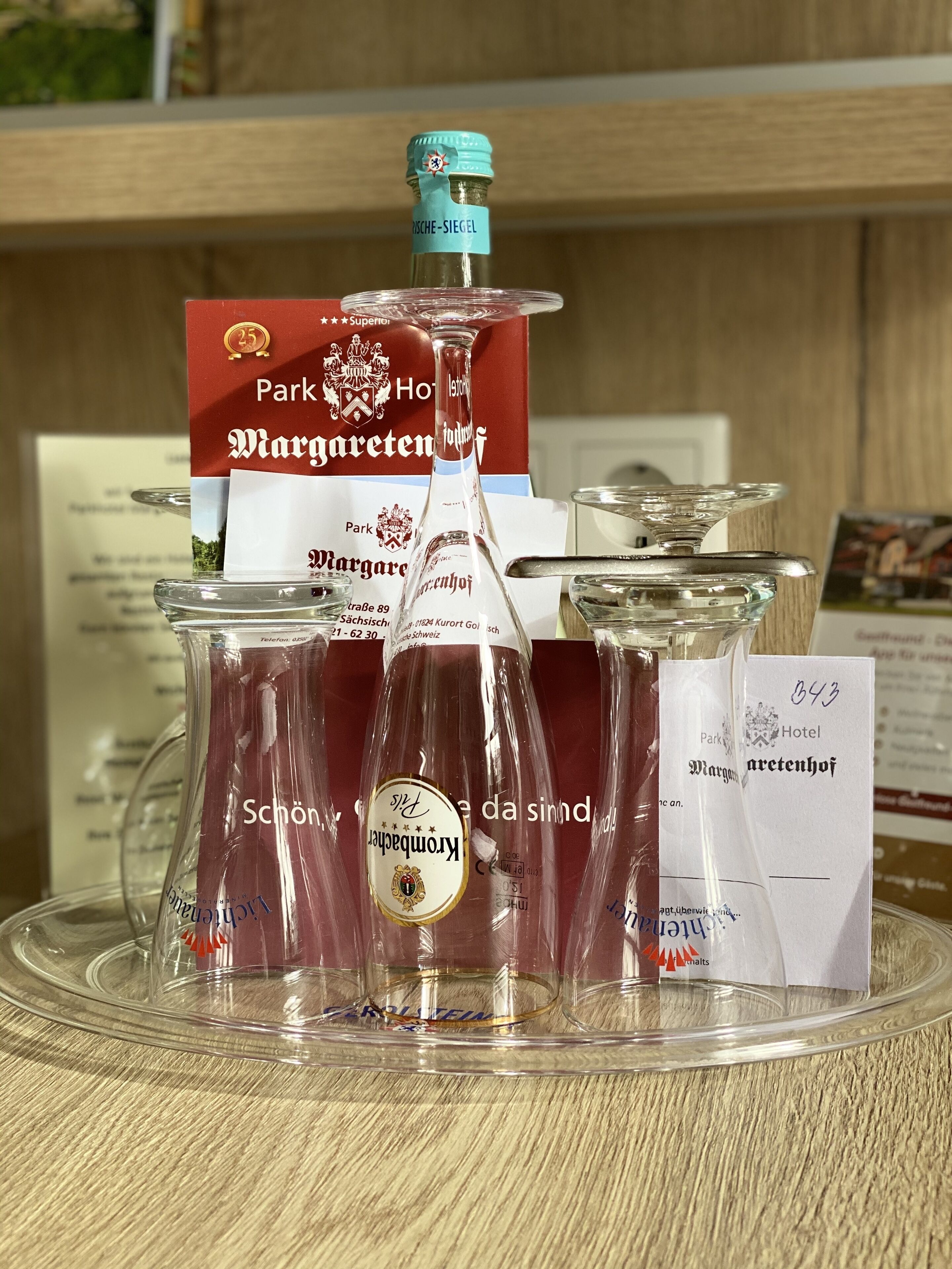 Uma garrafa de vinho Park Margarethen em um expositor com vários copos e um cardápio.