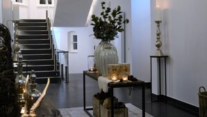 Um interior moderno com uma escada, uma mesa decorativa com velas e um vaso com folhagem.