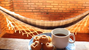 Uma rede, um prato com doces e uma xícara de café sobre uma mesa de madeira.