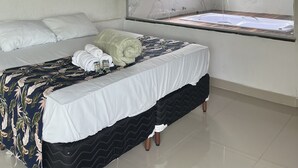 Quarto com cama, espelho grande, janela e banheira integrada.