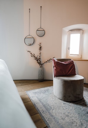 Quarto moderno com um banquinho redondo, um vaso com galhos e dois espelhos fixados na parede.
