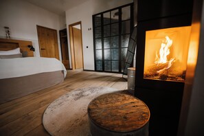 Quarto com cama, piso de madeira, janela grande e lareira.