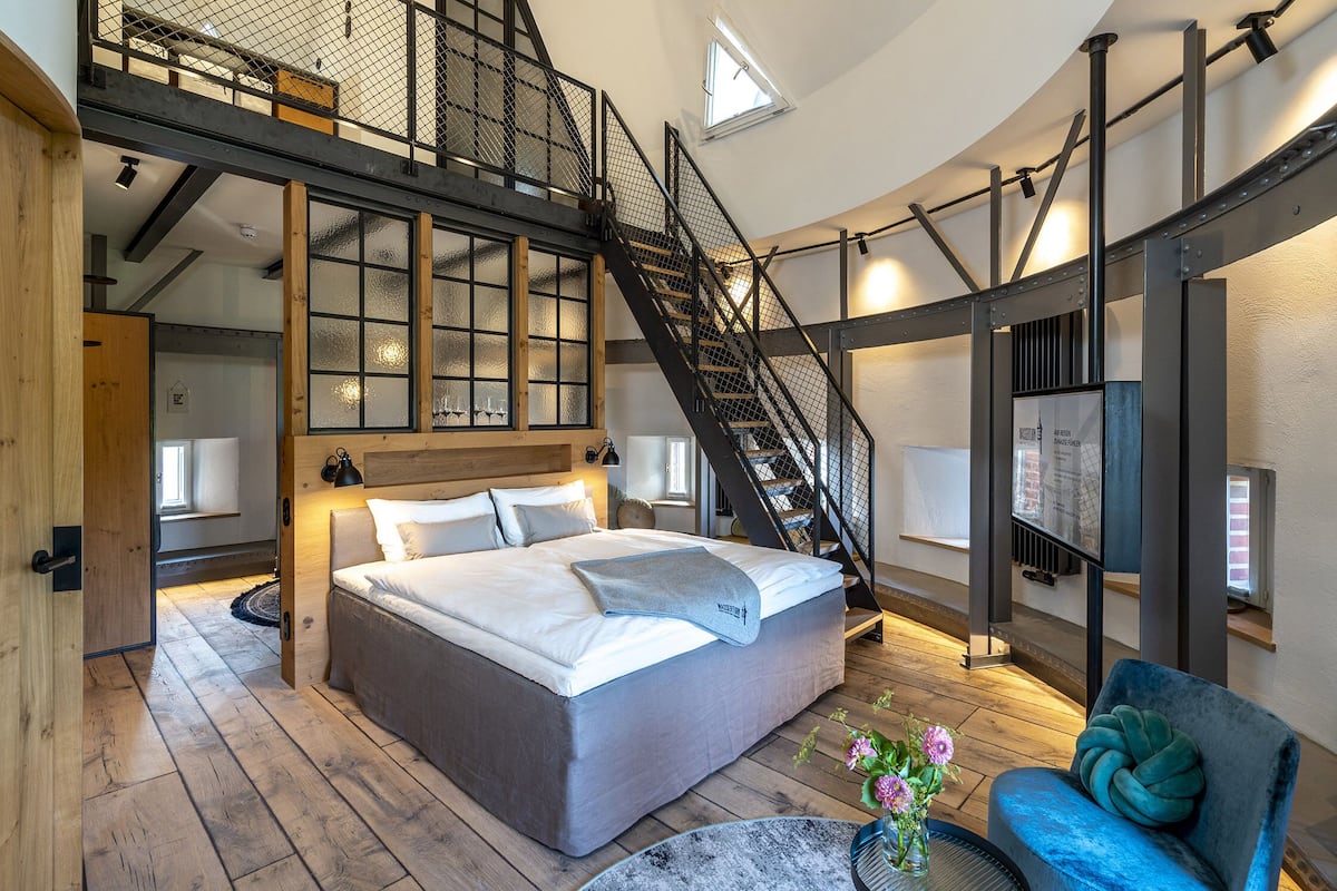 Quarto com uma cama grande, uma escada e vista para a sala de estar.