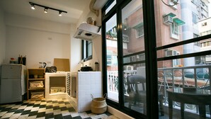 Uma cozinha compacta com piso xadrez, geladeira, pia e janela com vista para uma varanda com móveis de exterior.