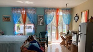 Quarto com uma cama, área de jantar com mesa e cadeiras, geladeira e televisão.