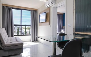 Uma sala de estar moderna com uma mesa de vidro, um sofá e uma TV fixada na parede.